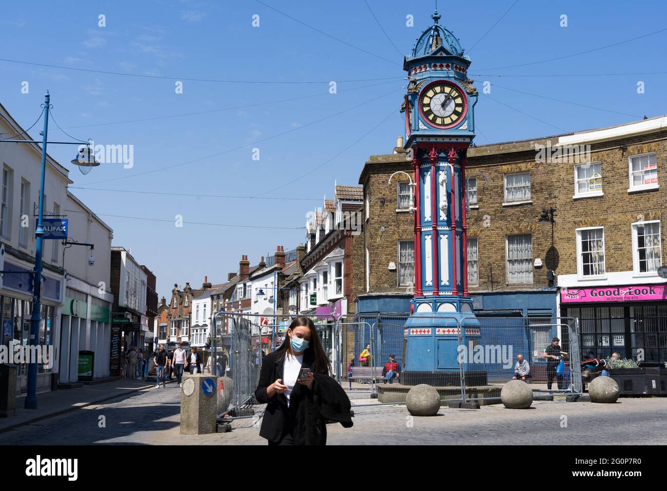 woman in face mask walk past the sheerness clock tower on high street ...