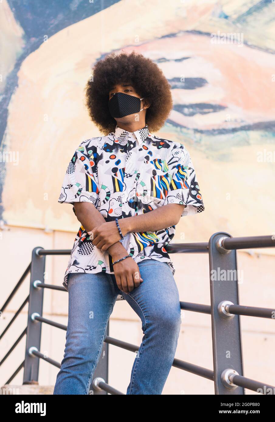 young black guy with afro hair wearing black mask standing leaning on a ...