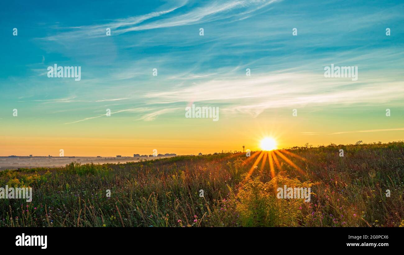 The first rays of the rising sun in a field on the outskirts of the ...
