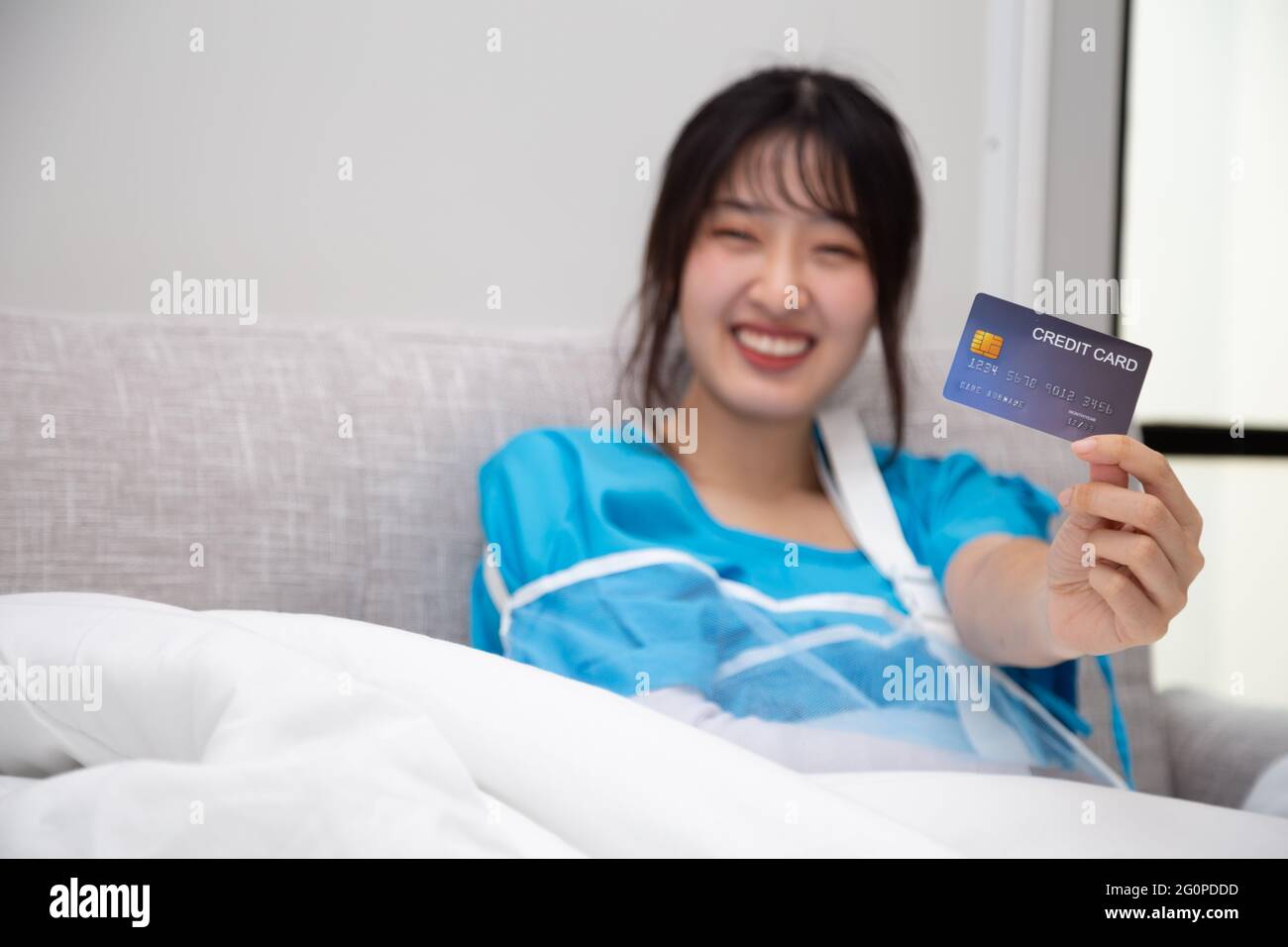 Asian woman holding insurance credit cards and wear patient suits on ...
