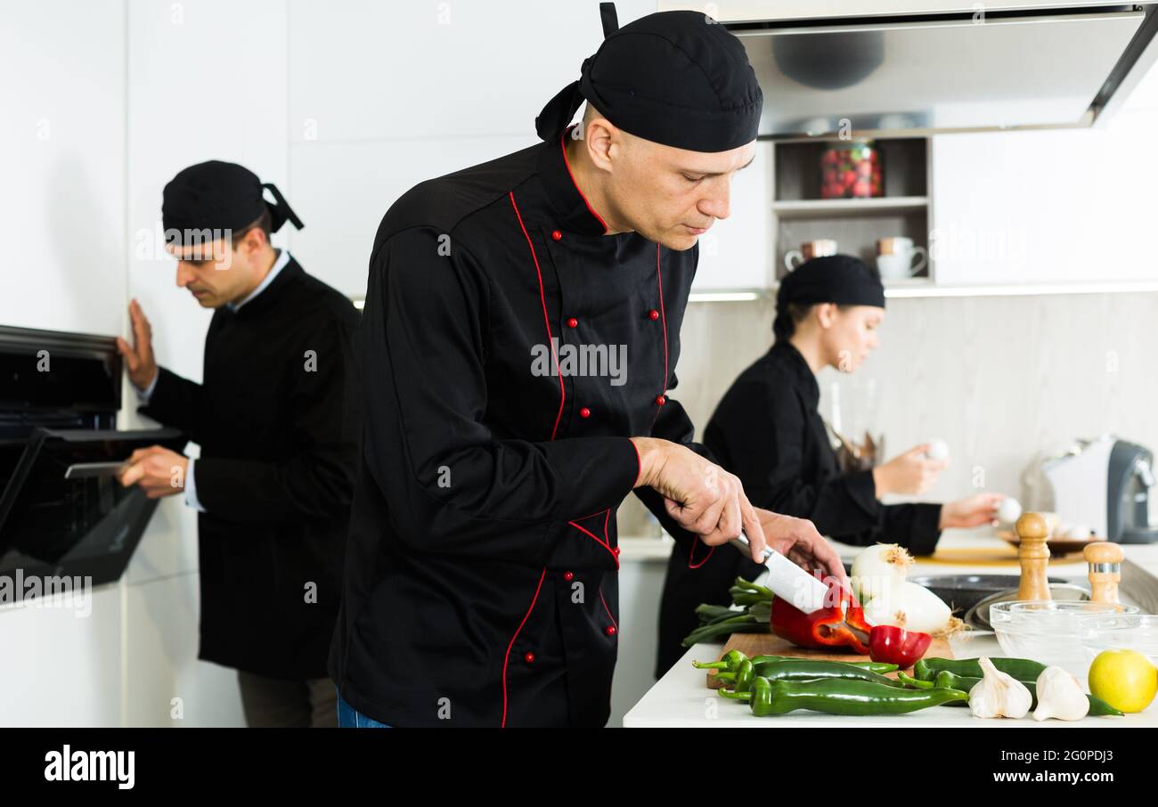 Female and male cooks wearing black uniform working on kitchen Stock ...
