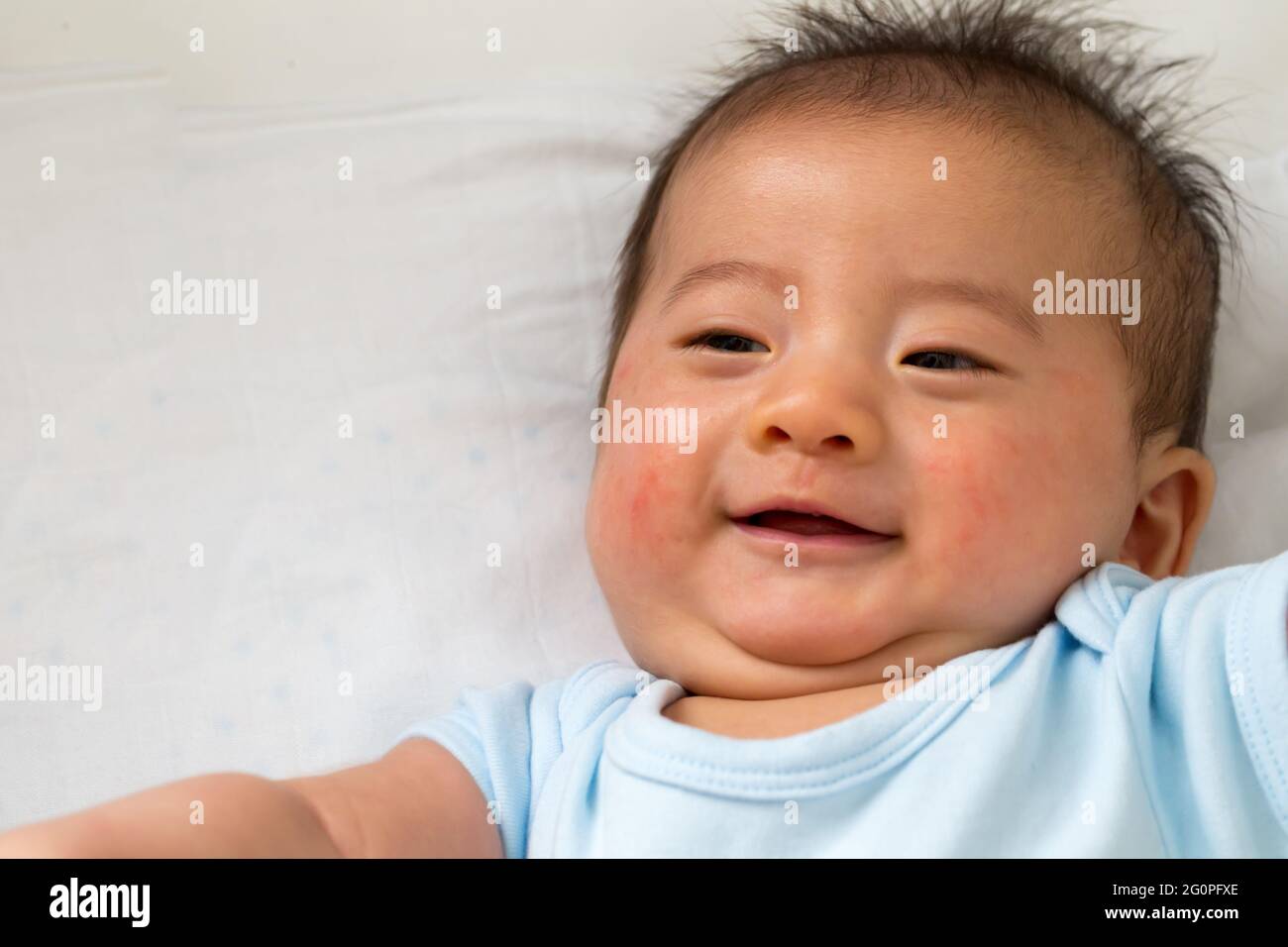 Happy little Asian baby smiling while lying on white bed Stock Photo ...