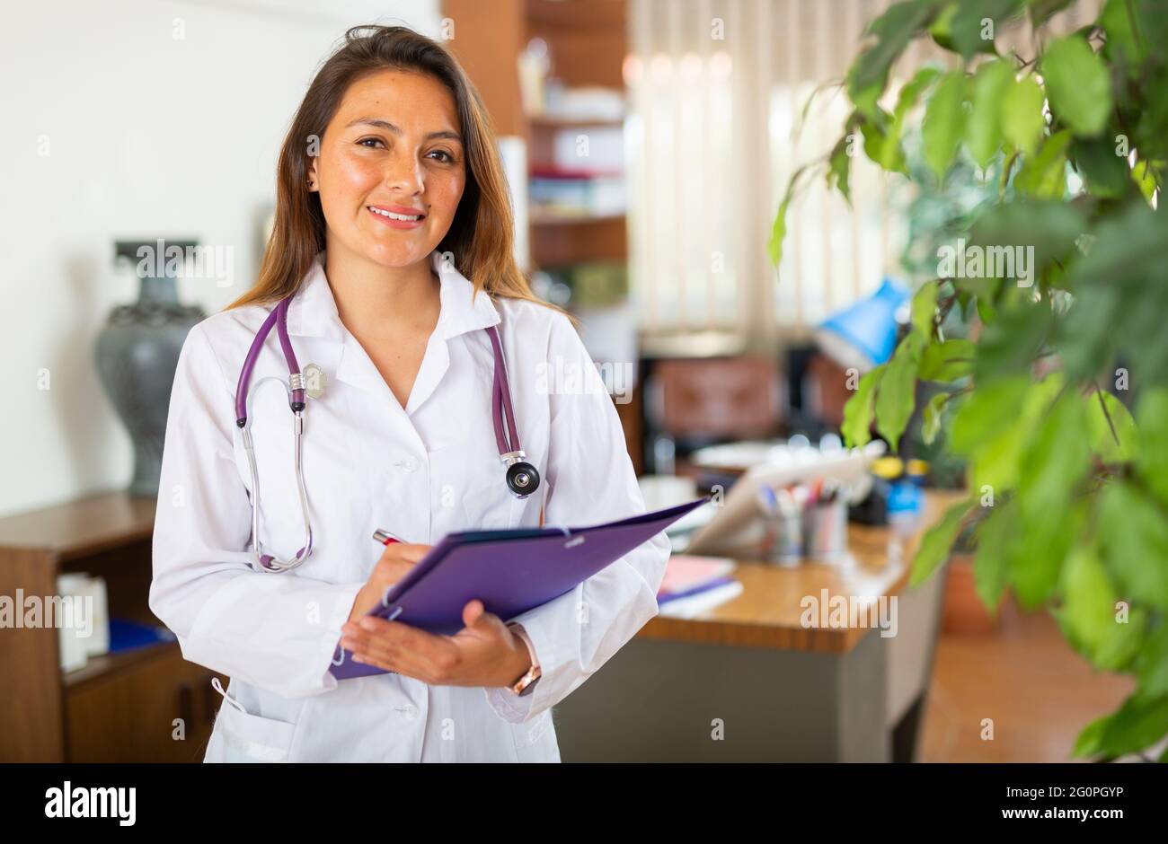 Young female doctor filling out medical form at clipboard Stock Photo ...