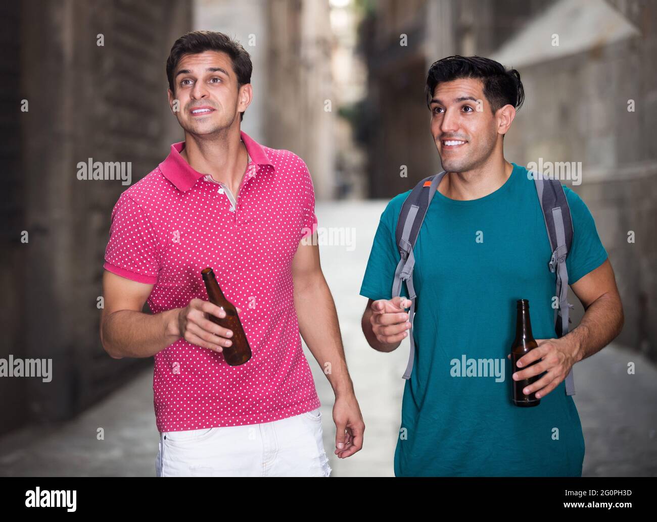 Two male friends are walking and drinking beer Stock Photo - Alamy