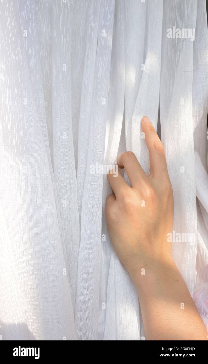 A photo of a hand touching white voile curtain Stock Photo - Alamy