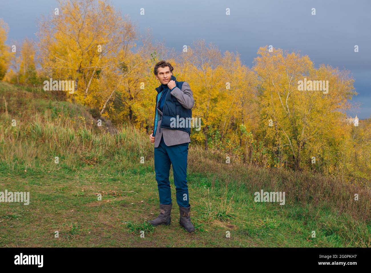 Tall handsome man walking outdoor in yellow autumn forest on the hill ...