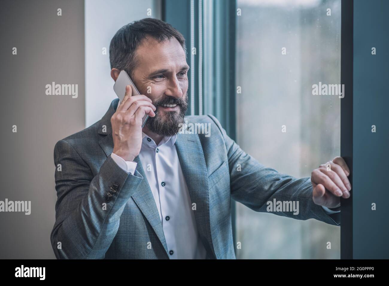 Successful man in suit talking positively on smartphone Stock Photo - Alamy