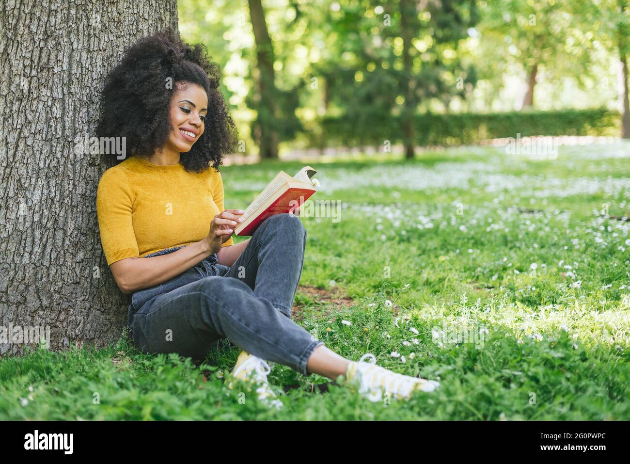 Pretty afro woman reading a book in a garden Stock Photo - Alamy