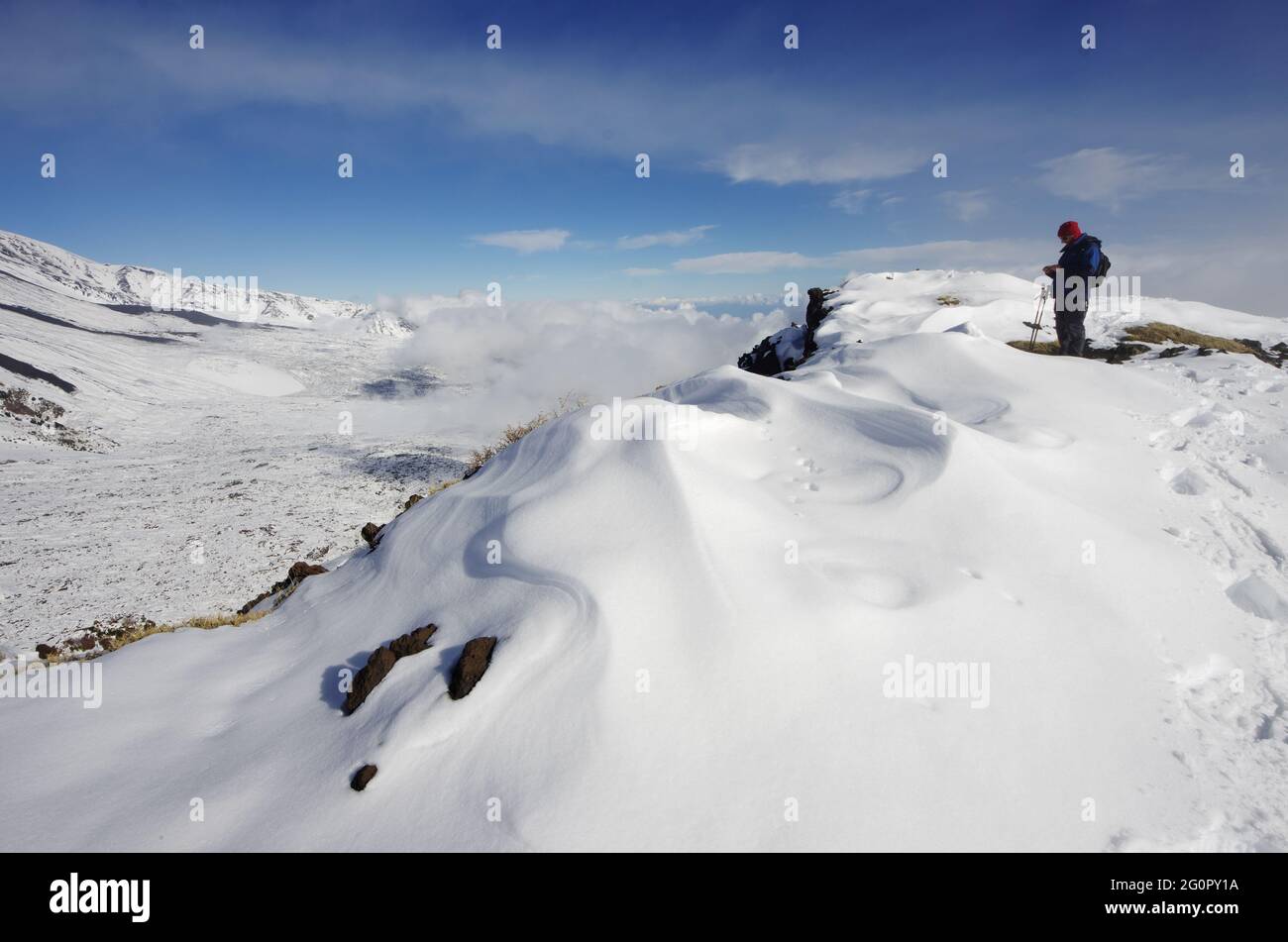 one hiker at the summit of a high mountain trail covered with snow in ...