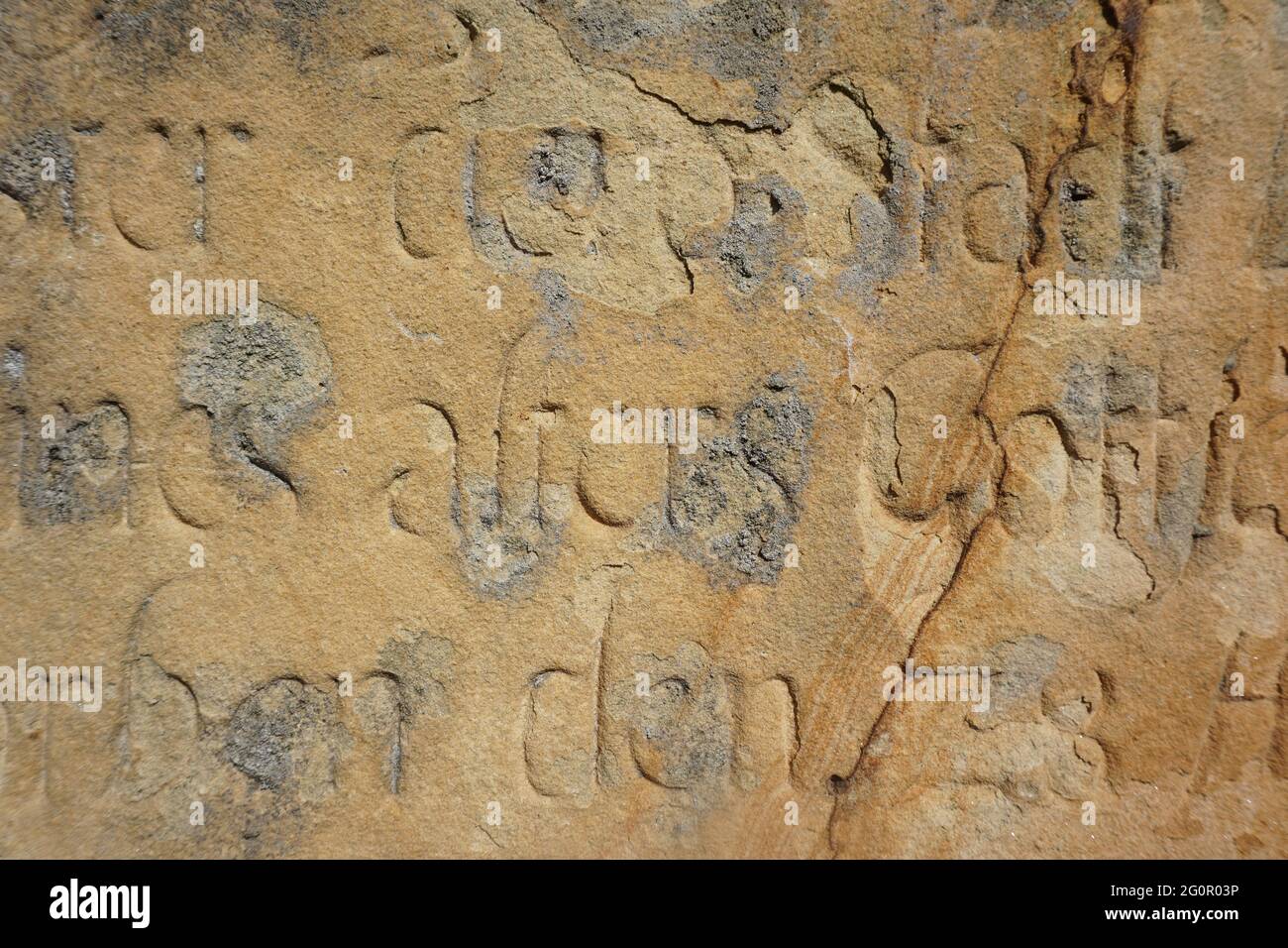 Part of an old tombstone of sandstone. Meant as background. Text on the ...