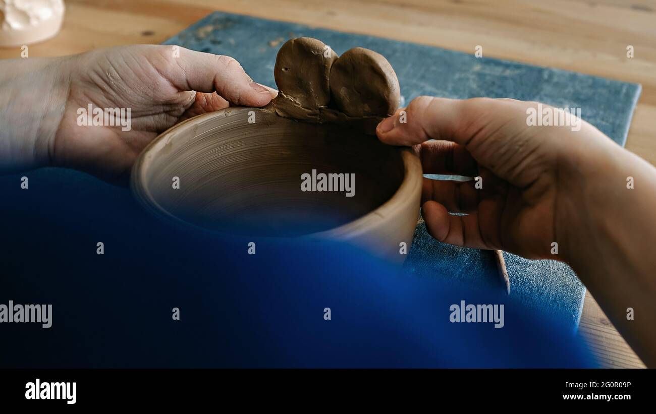 Hands of a young artist, modeling a clay bowl in art studio ...
