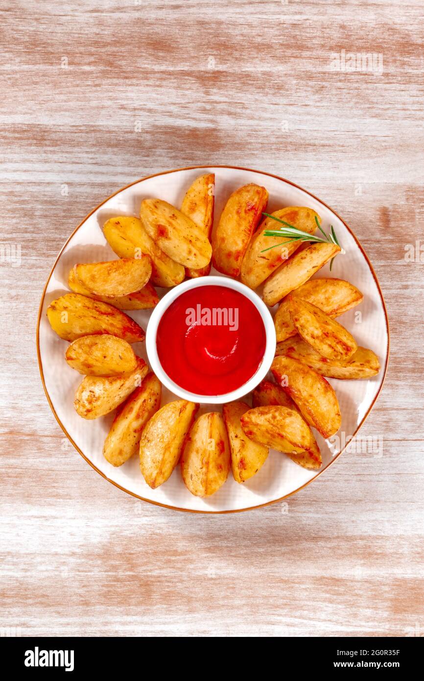 Baked potato wedges, shot from above on a rustic background, a simple ...