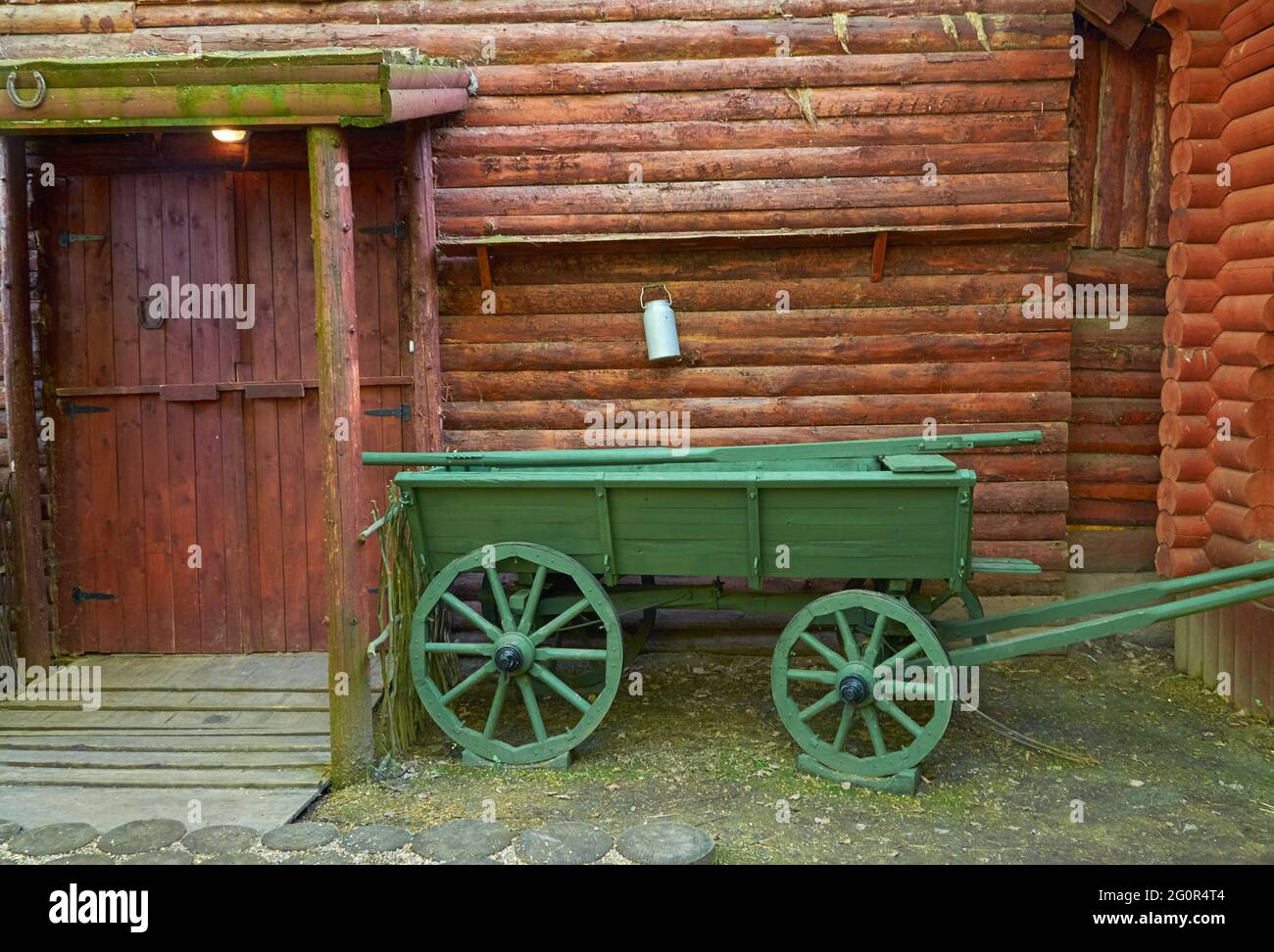 A green wooden cart stands at the entrance to a wooden house Stock ...