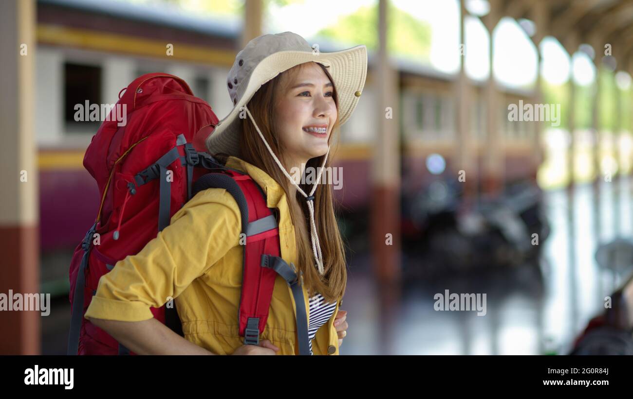 Side view of friendly young female backpacker smiling when arriving at ...