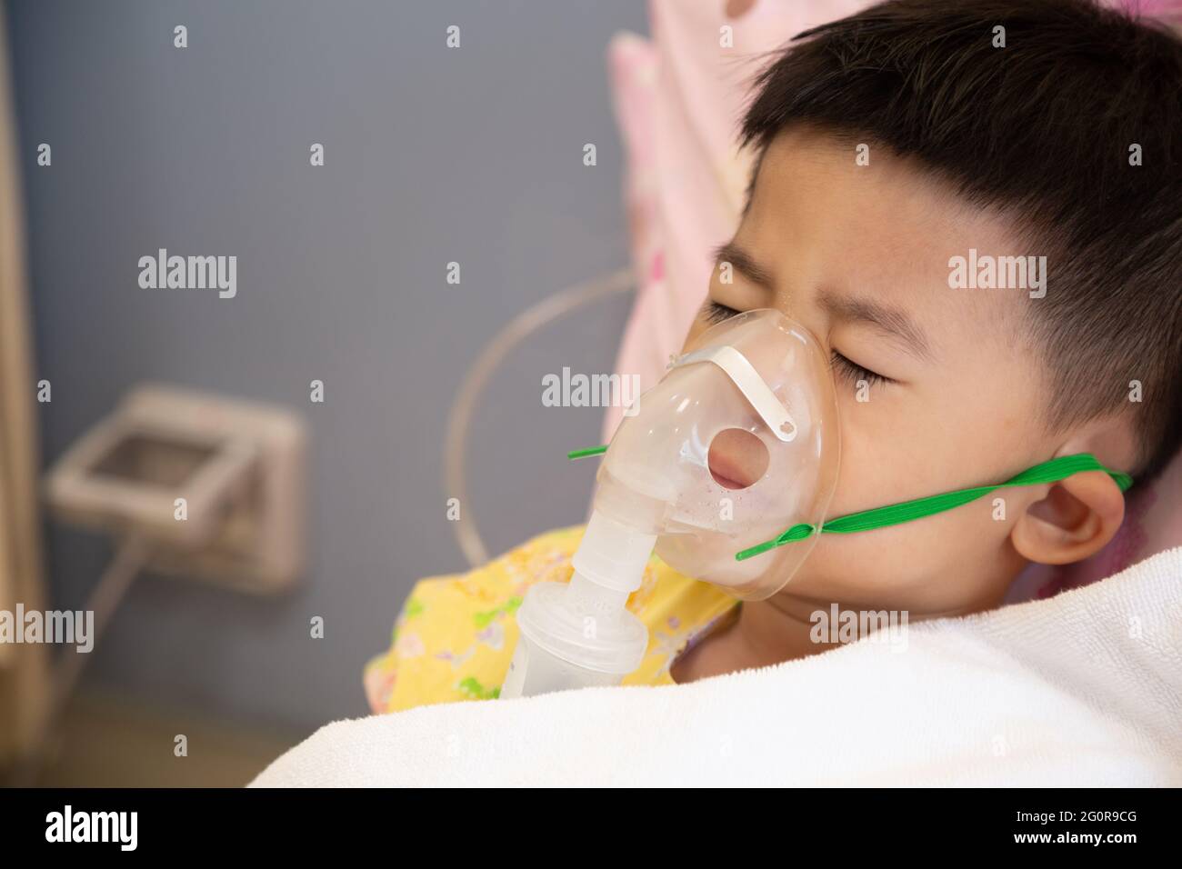 Asian little boy making inhalation with nebulizer at hospital ...