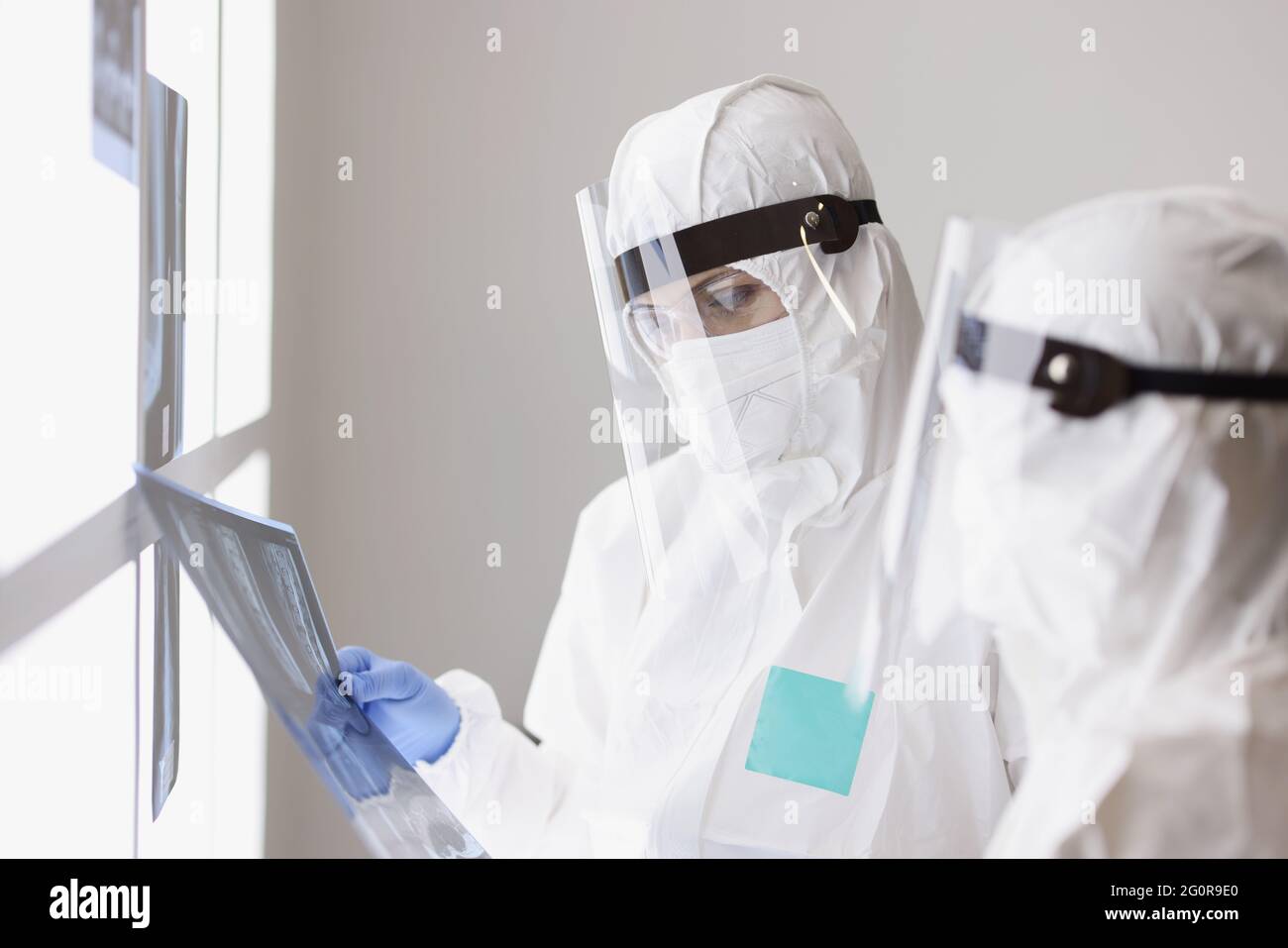 Doctors in protective anti-plague suits on screens looking at x-ray of ...