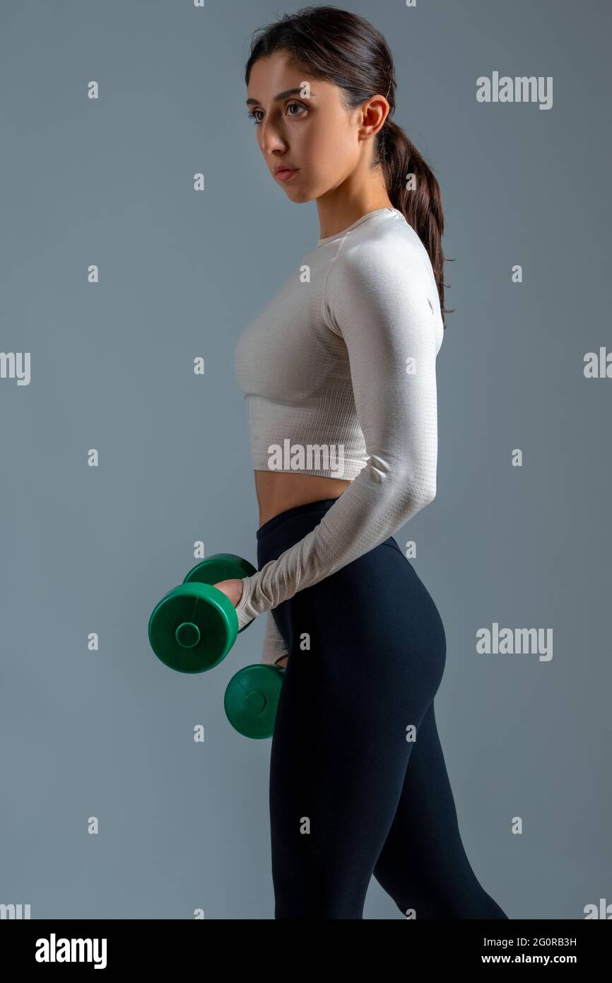 Girl performing arm exercises with dumbbells on grey background Stock ...