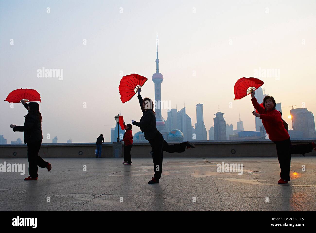 China. Shanghai. Chinese women dance with red fans on the bund in ...