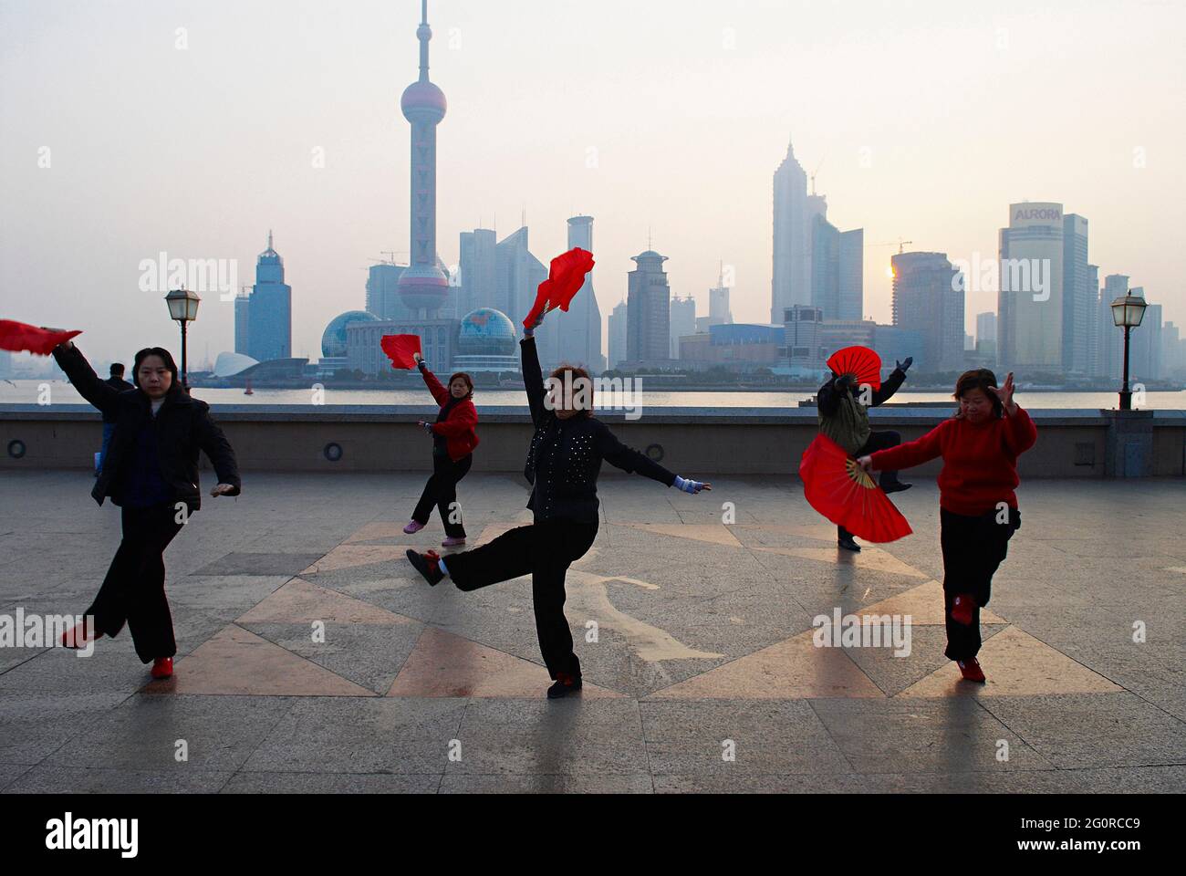 China. Shanghai. Chinese women dance with red fans on the bund in ...