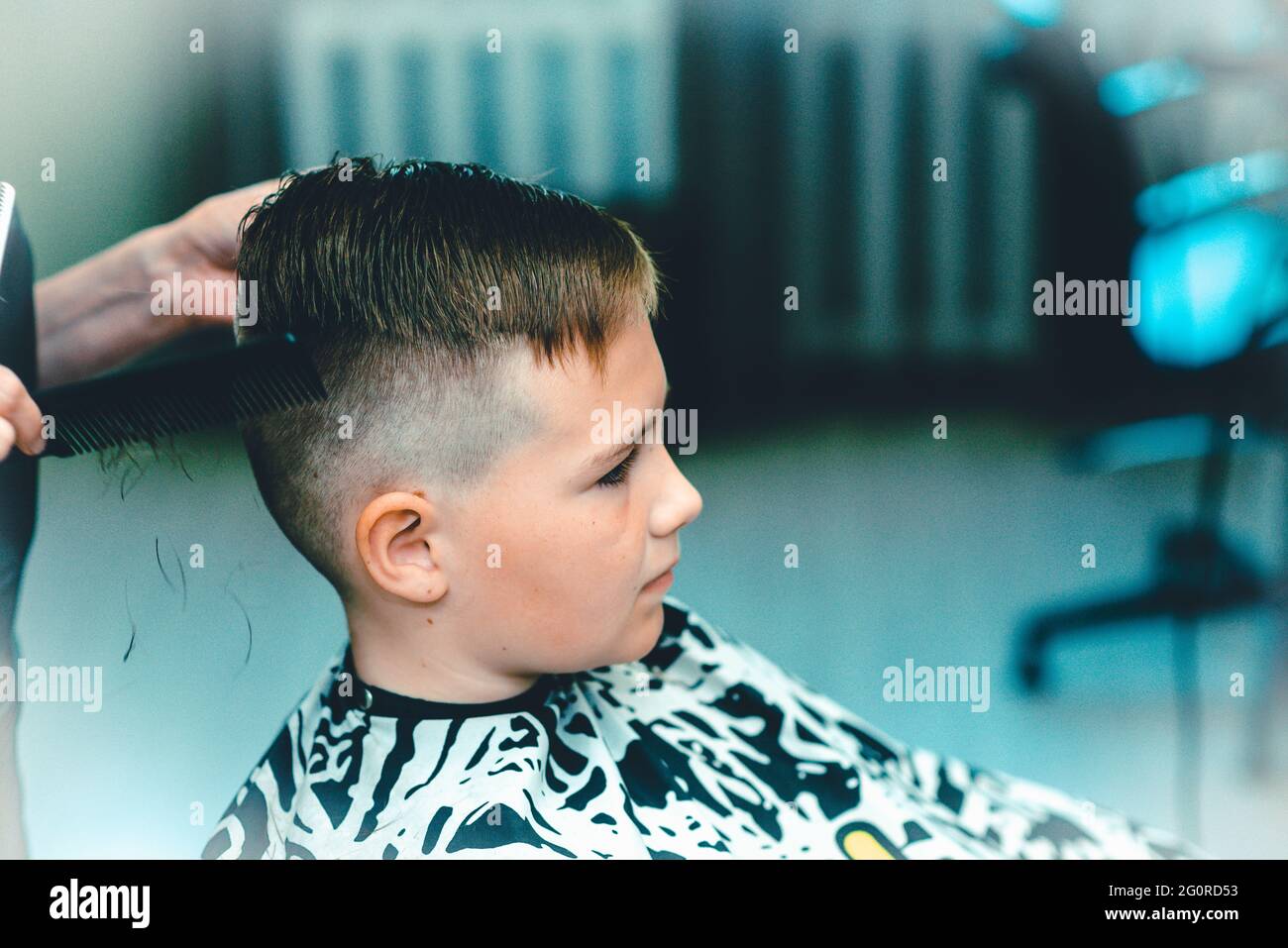 Cute european boy getting hairstyle, hairdresser makes a hairstyle for ...