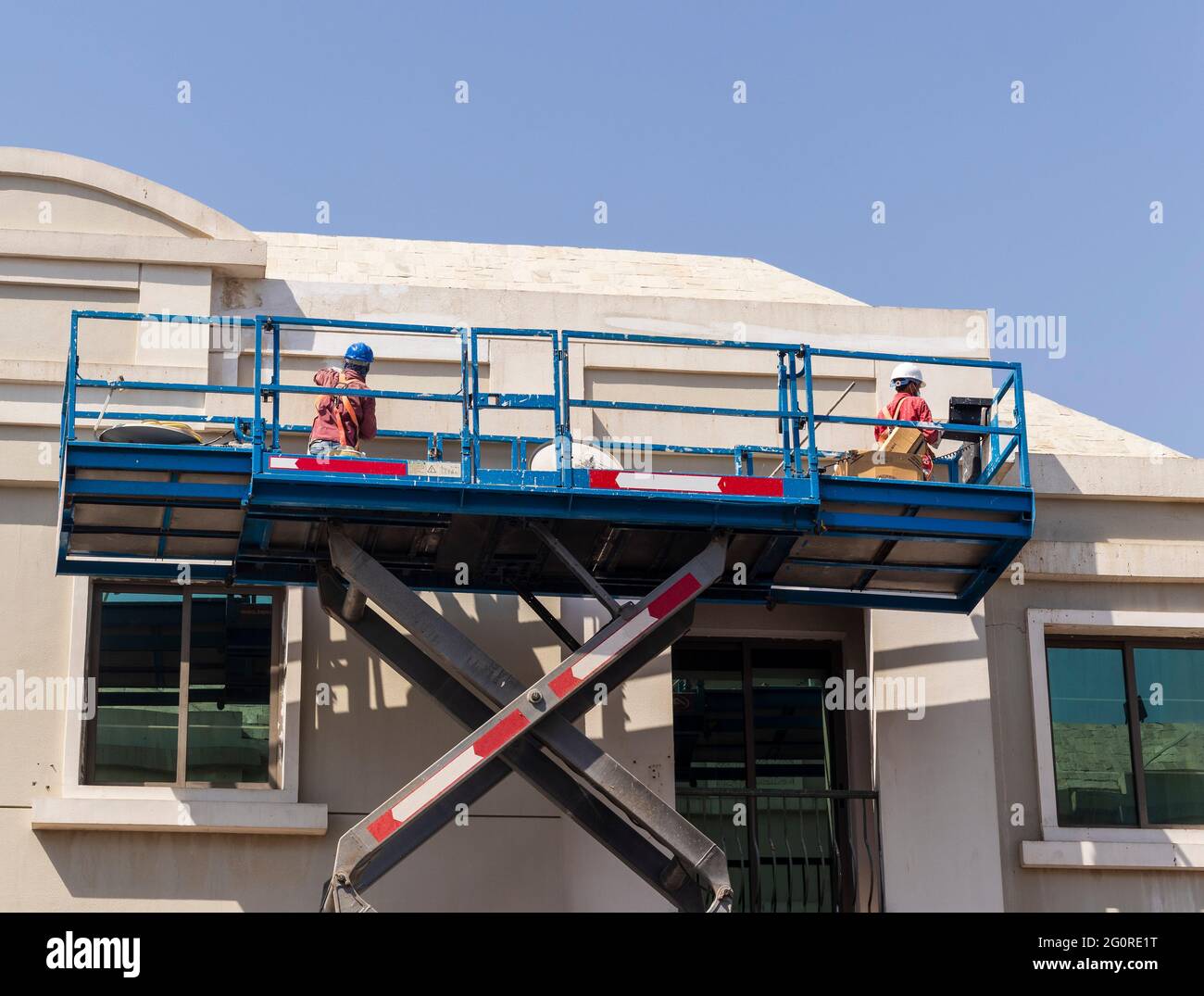 Shot of a maintenance workers working at heights, repairing facade of ...