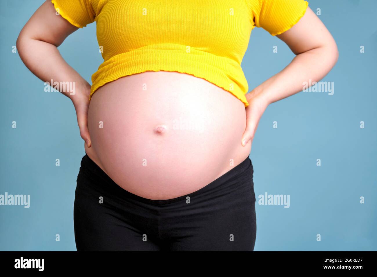 Belly of a pregnant woman on a blue background Stock Photo - Alamy