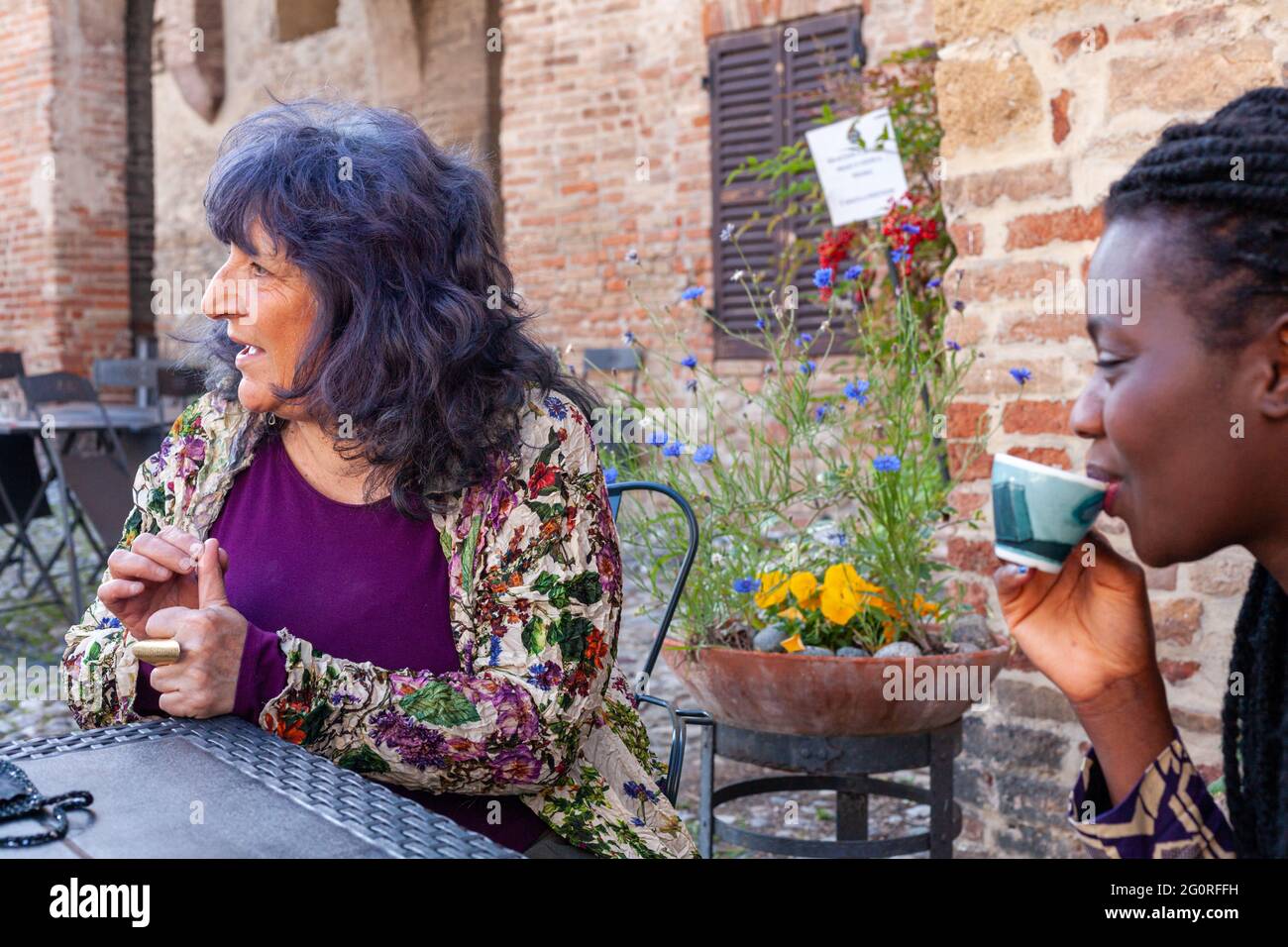 Hispanic and African-American women sitting around a table and drinking ...