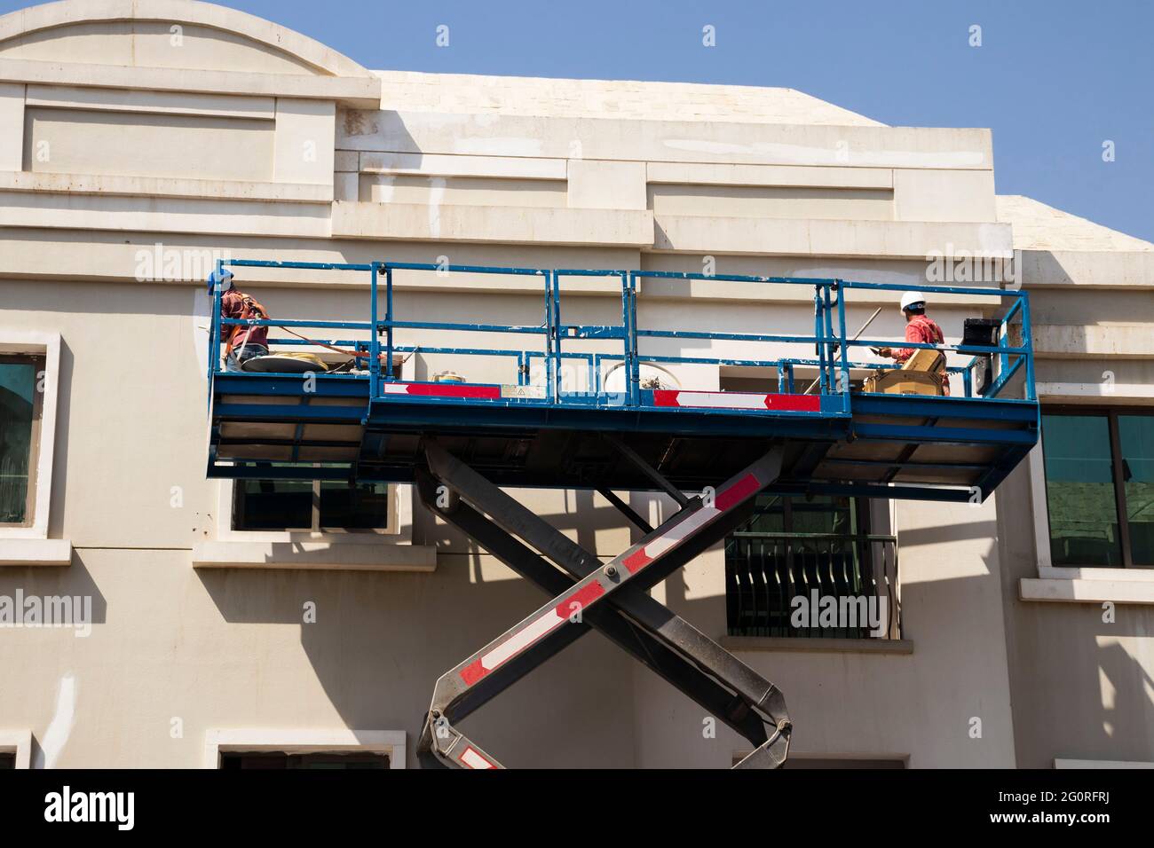 Shot of a maintenance workers working at heights, repairing facade of ...