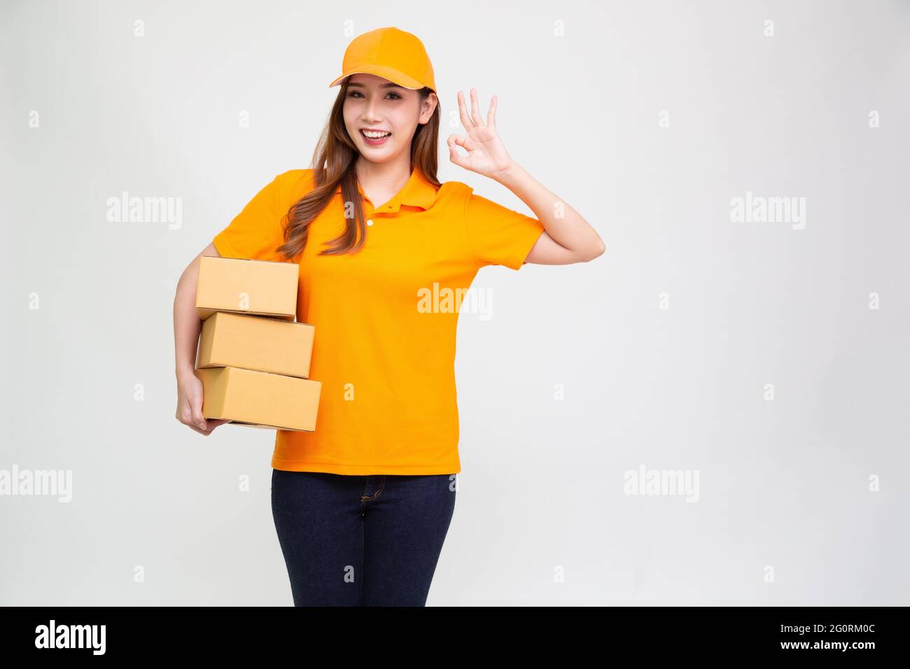 Asian delivery woman holding parcel box in orange uniform isolated on ...