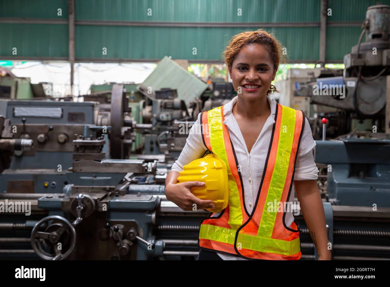 Female industrial engineer holding hard hat while standing in the heavy ...