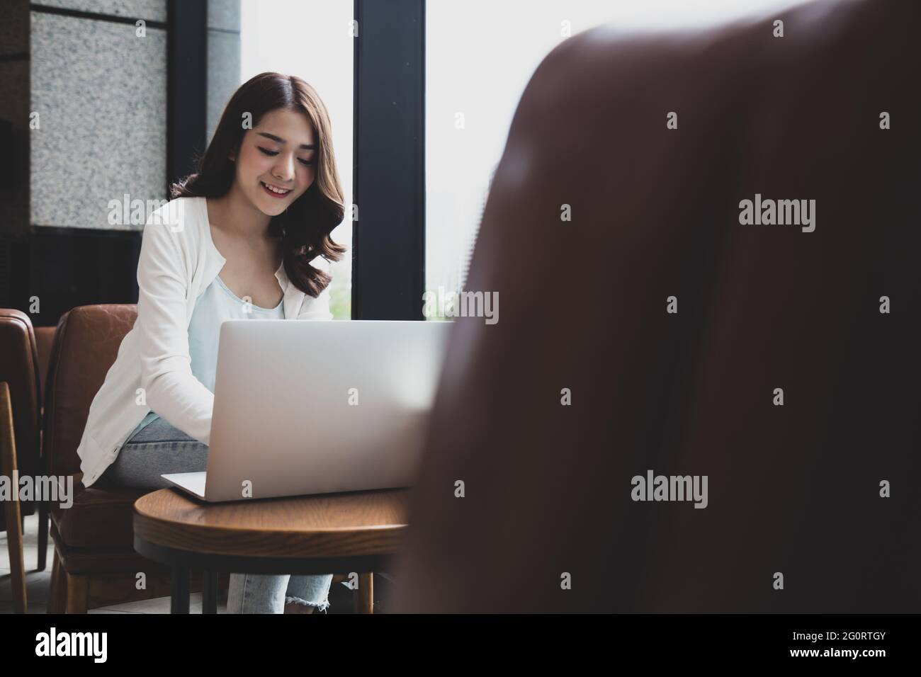 Cheerful Asian female freelancer typing on keyboard laptop computer ...