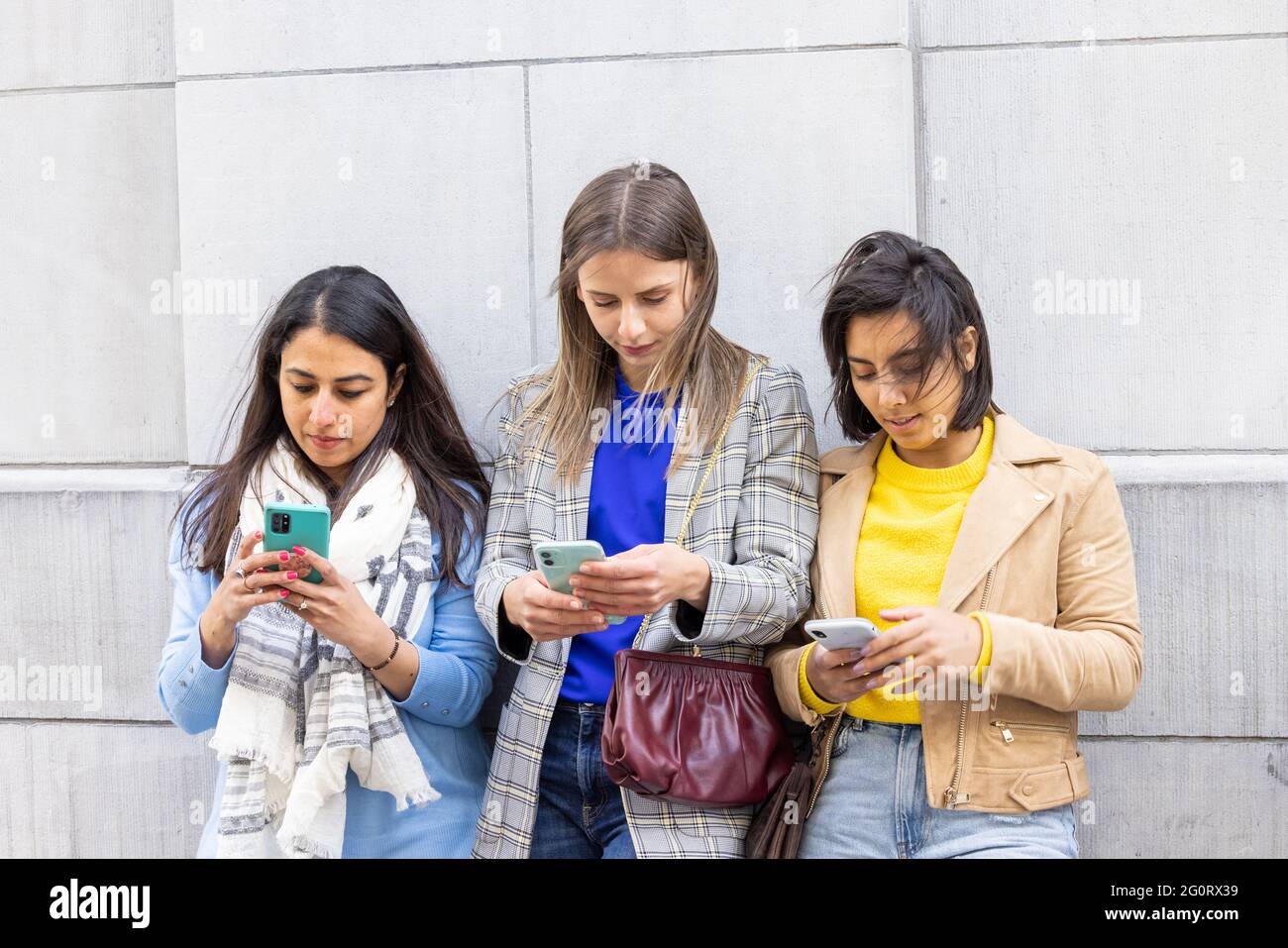 Group of beautiful young female friends of different race using smart ...