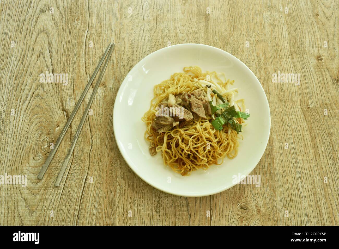 Chinese yellow egg noodles topping braised pork on plate Stock Photo ...