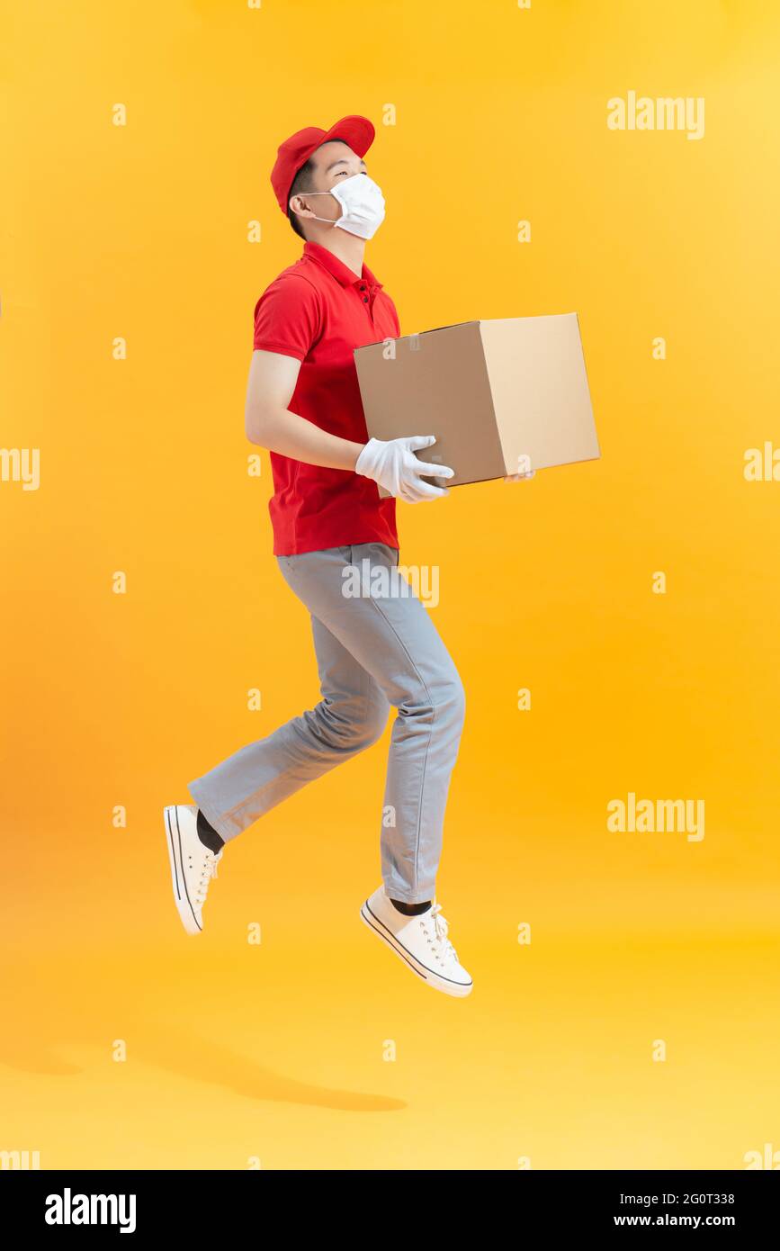 delivery man with face mask and gloves holding a cardboard box and ...