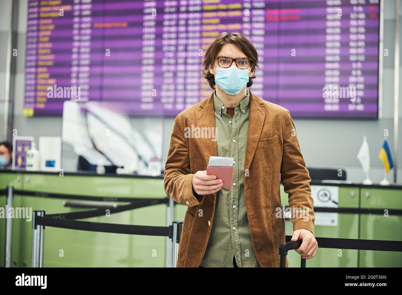 Young man in protective face mask waiting for the flight at airport ...