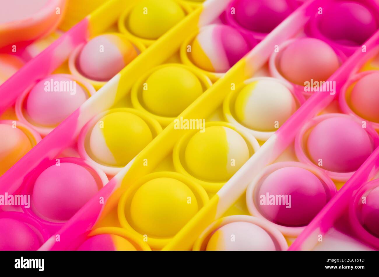 Close-up of a brightly colored Pop it fidget toy on a colored ...