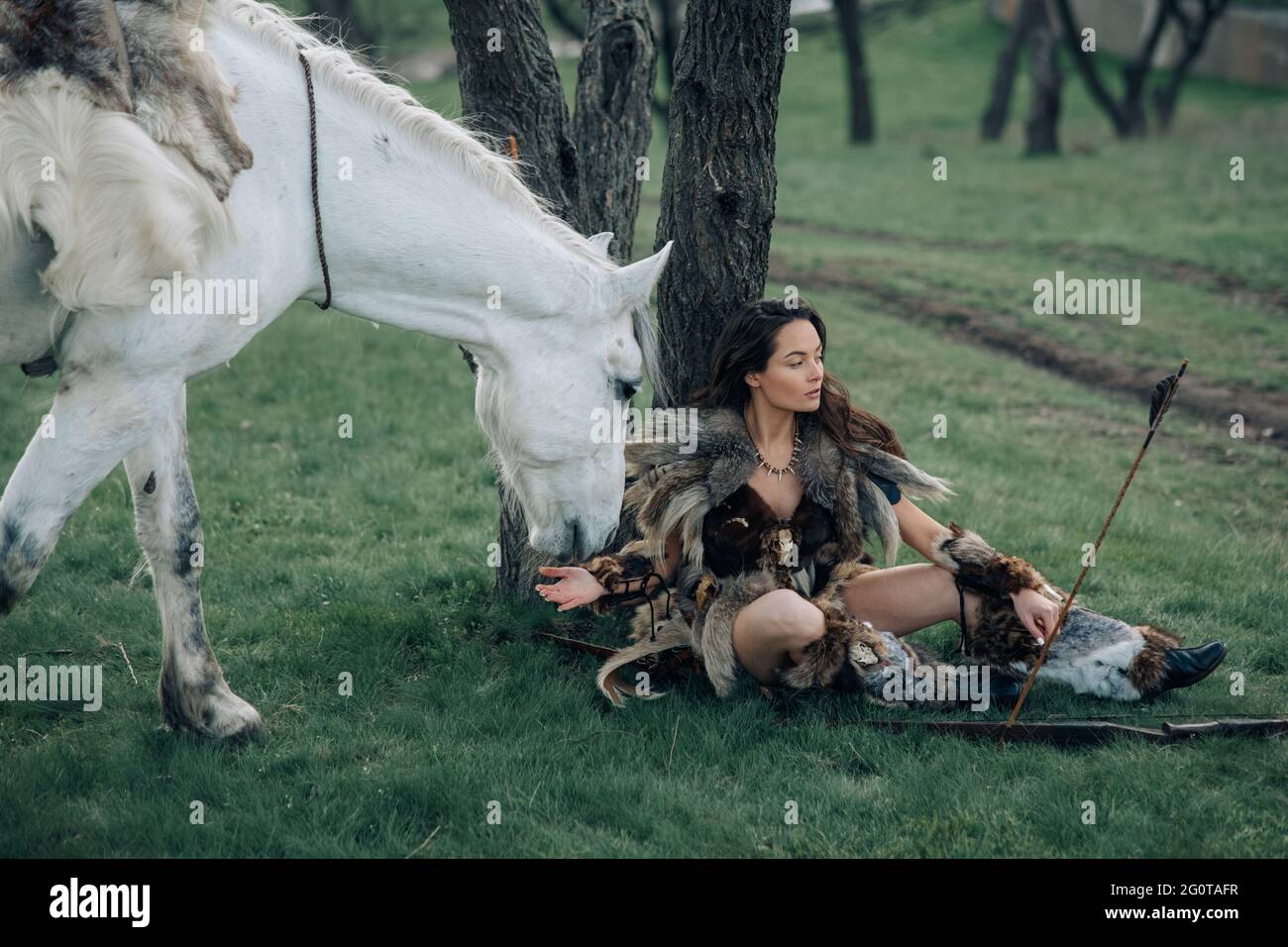 Woman in image of ancient warrior amazon sits and rests with bow and ...