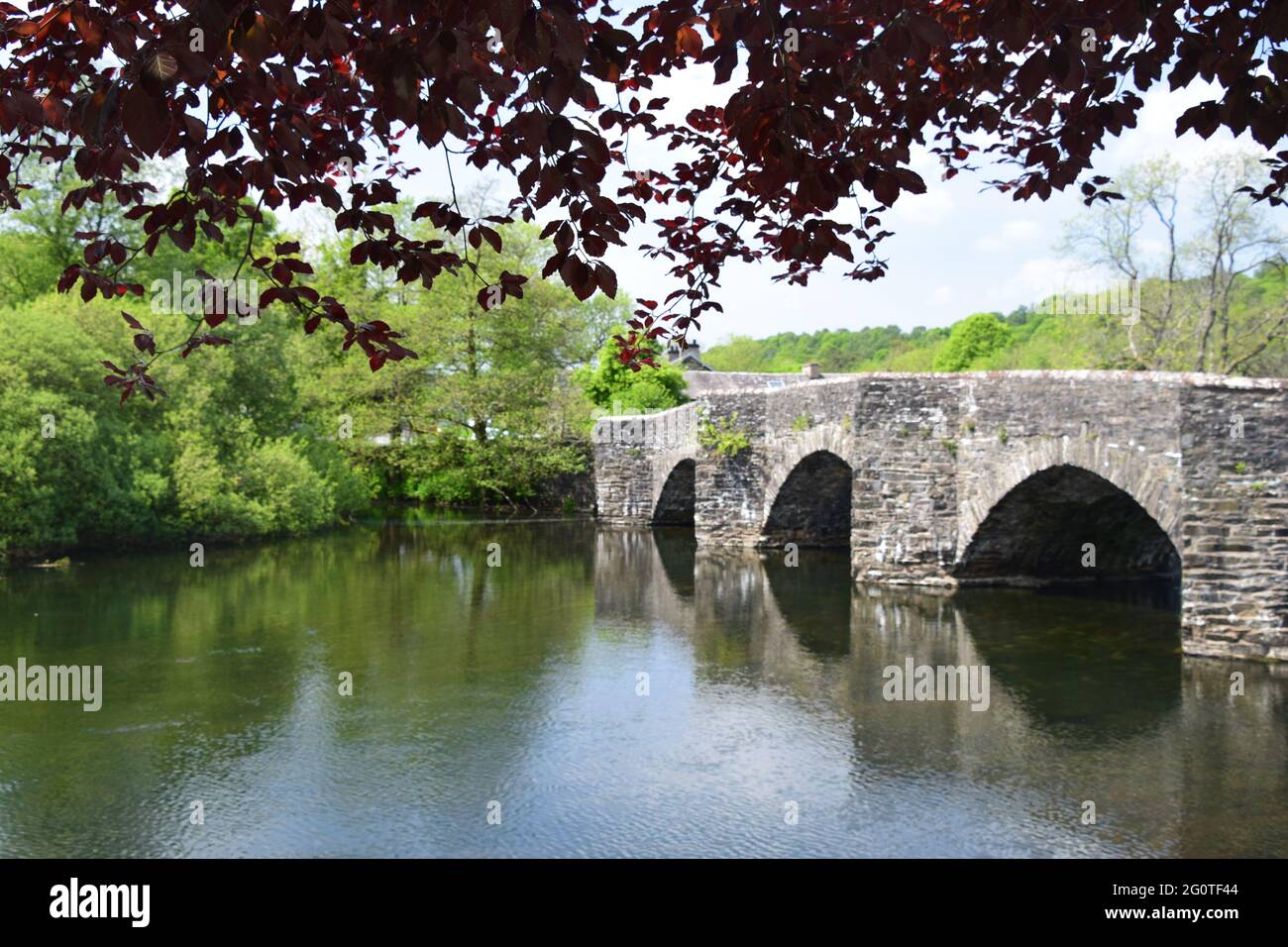 The river Leven flowing through the arches of the old stone bridge ...