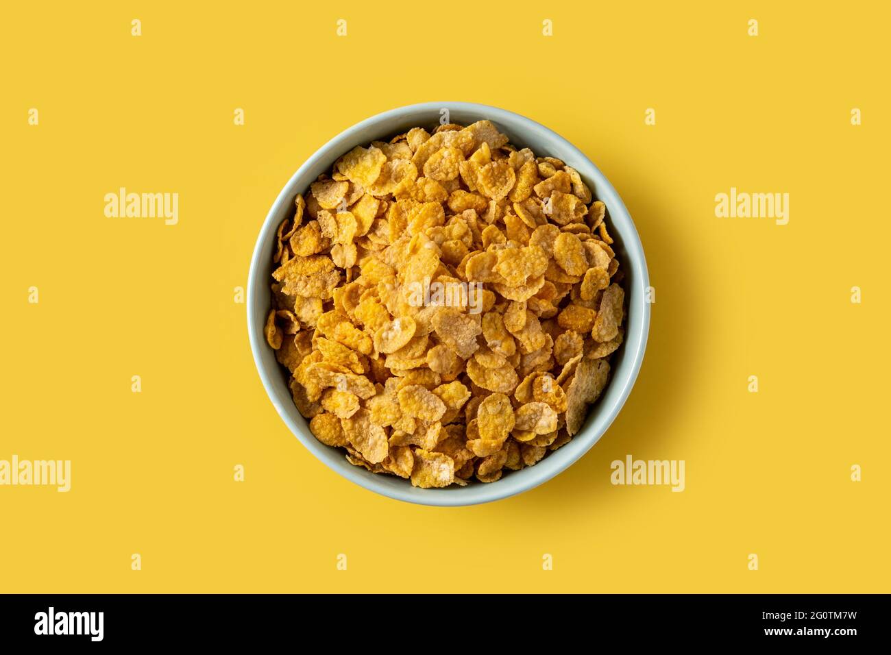 Corn flakes in a blue bowl on yellow background Stock Photo - Alamy