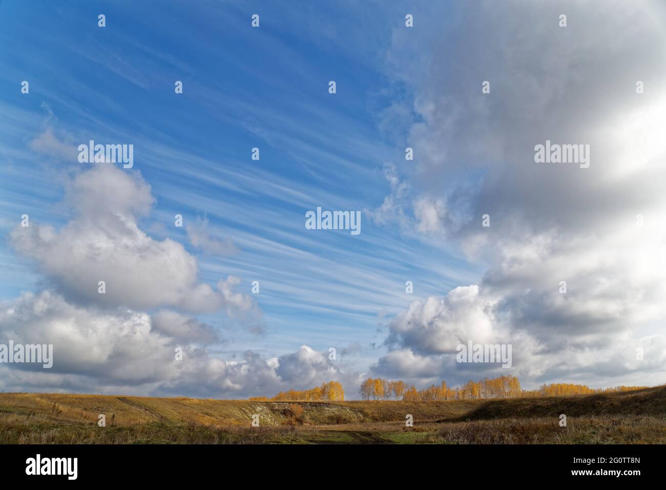 A blue sky with clouds over a autumn landscape with trees in the ...