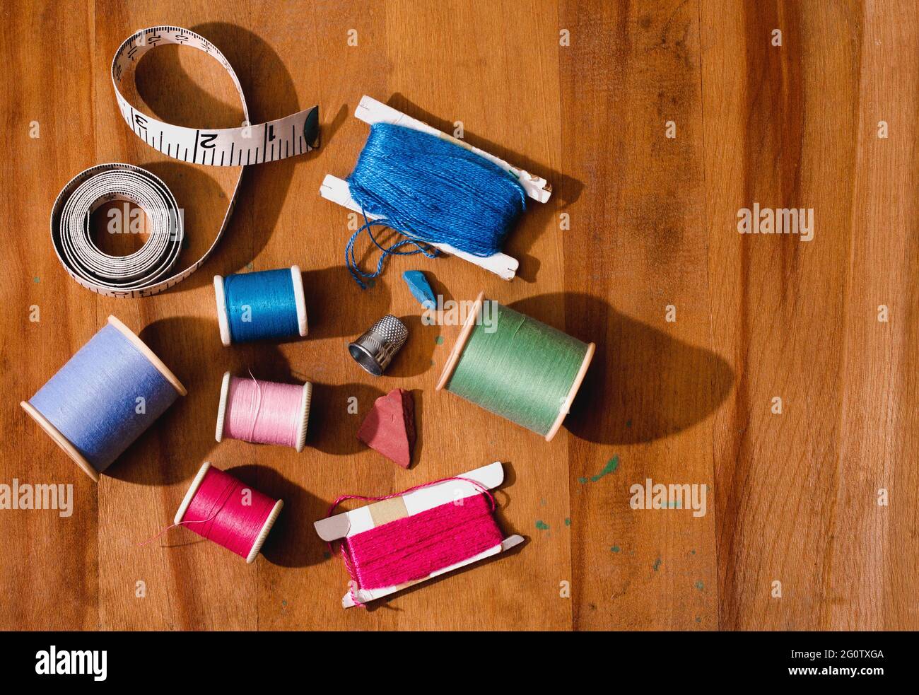 Sewing thread spools and accessories on wood table with copy space ...