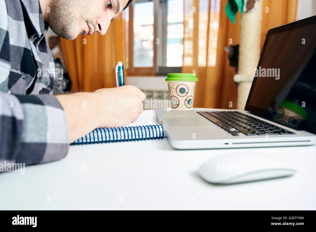 Man writing in a notebook while using a computer Stock Photo - Alamy