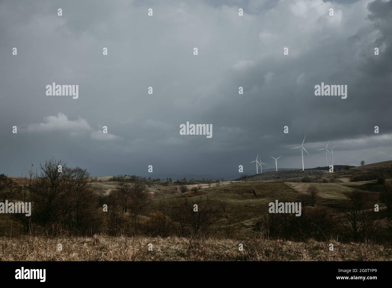 Farm of wind turbines for renewable wind energy on far horizon on hills ...