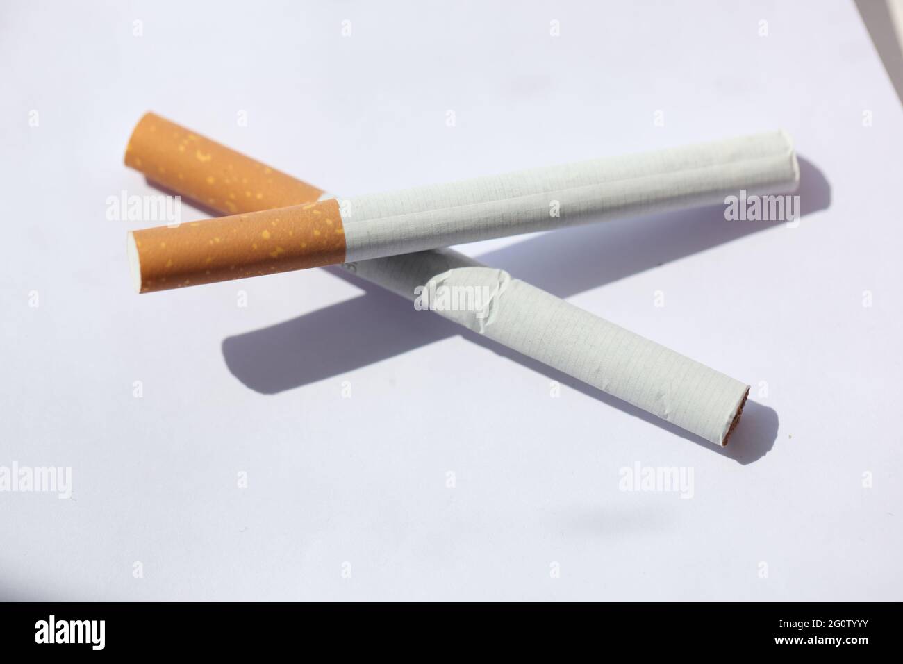 Two cigarettes laying at cross-angle on white background Stock Photo ...