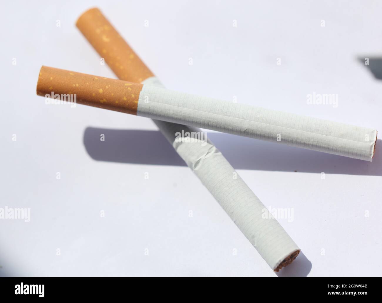 Two cigarettes laying across each other on a white background Stock ...