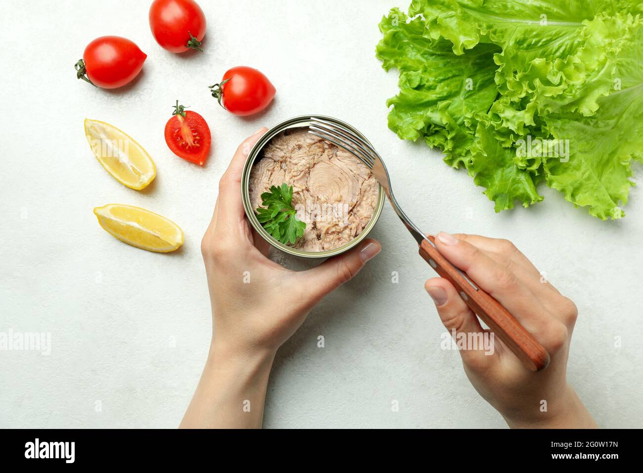 Concept of tasty eating with canned tuna on white textured background ...