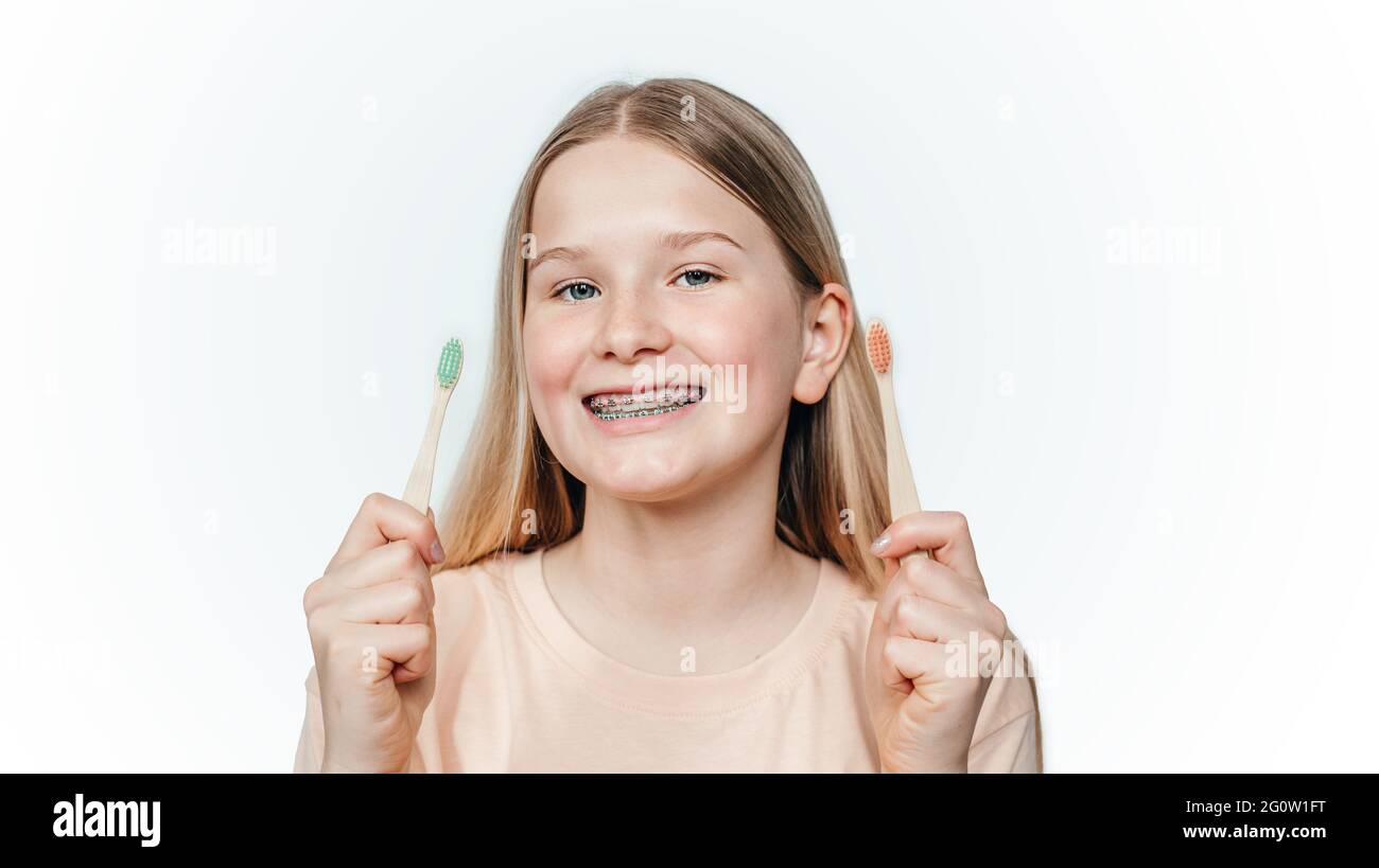 Smiling blonde girl with orthodontic braces holding eco friendly bamboo ...