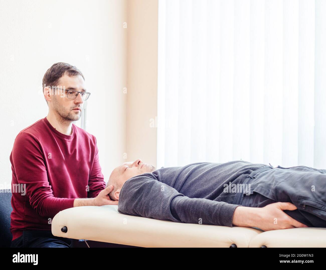 Craniosacral therapy practitioner giving a male patient CST osteopathic ...