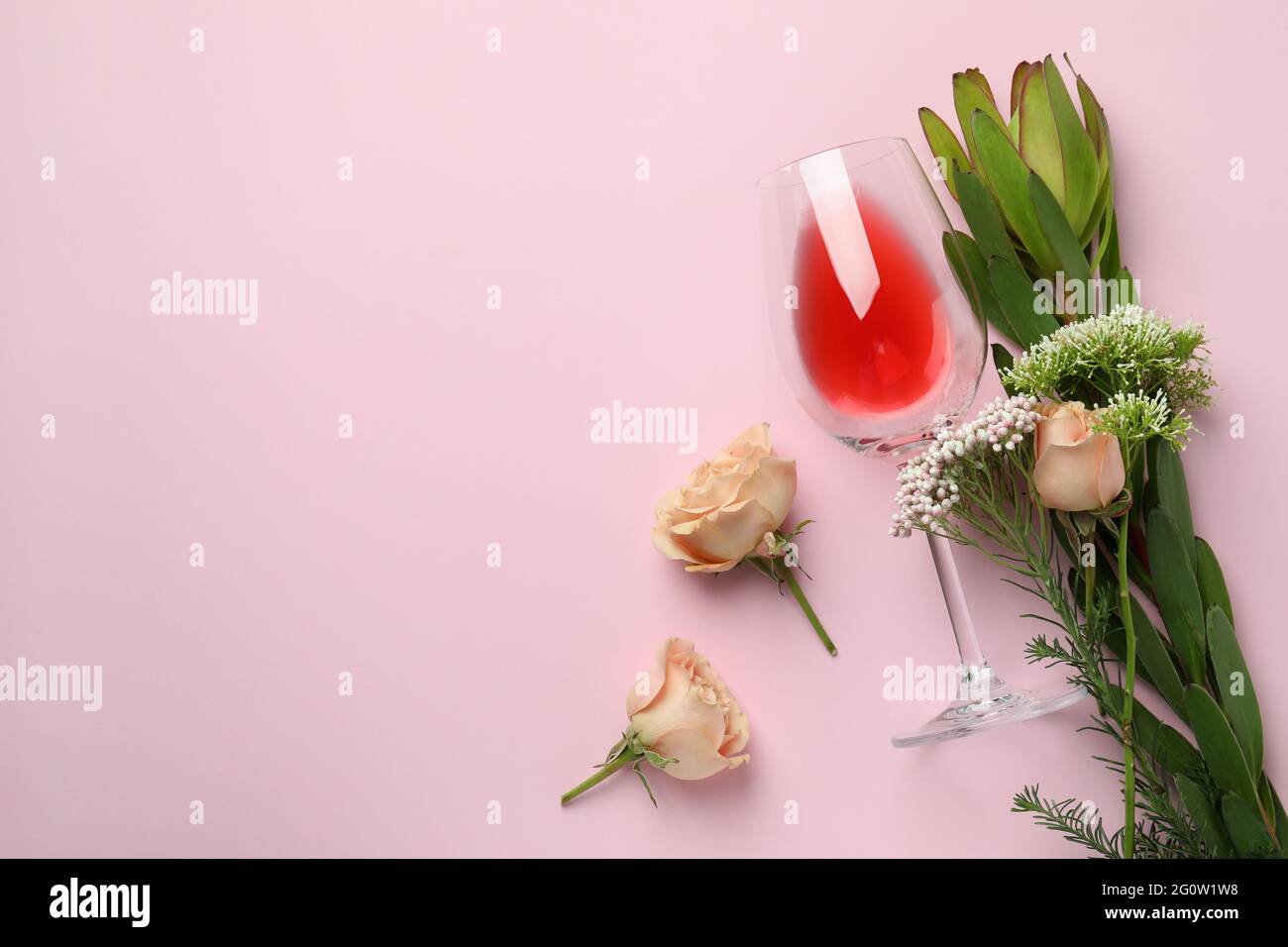 Glass of wine and flowers on pink background Stock Photo - Alamy