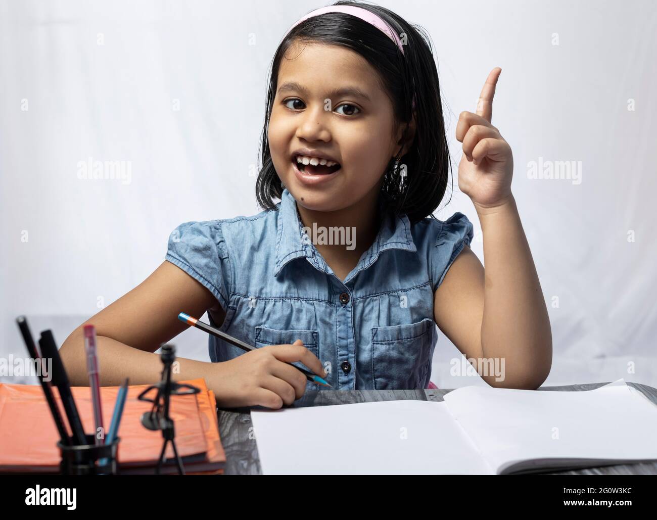 A pretty Indian girl child thinking and looking at camera while ...